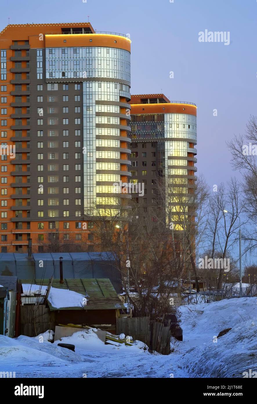 New and old houses in the evening. Multi-storey new buildings near old ...