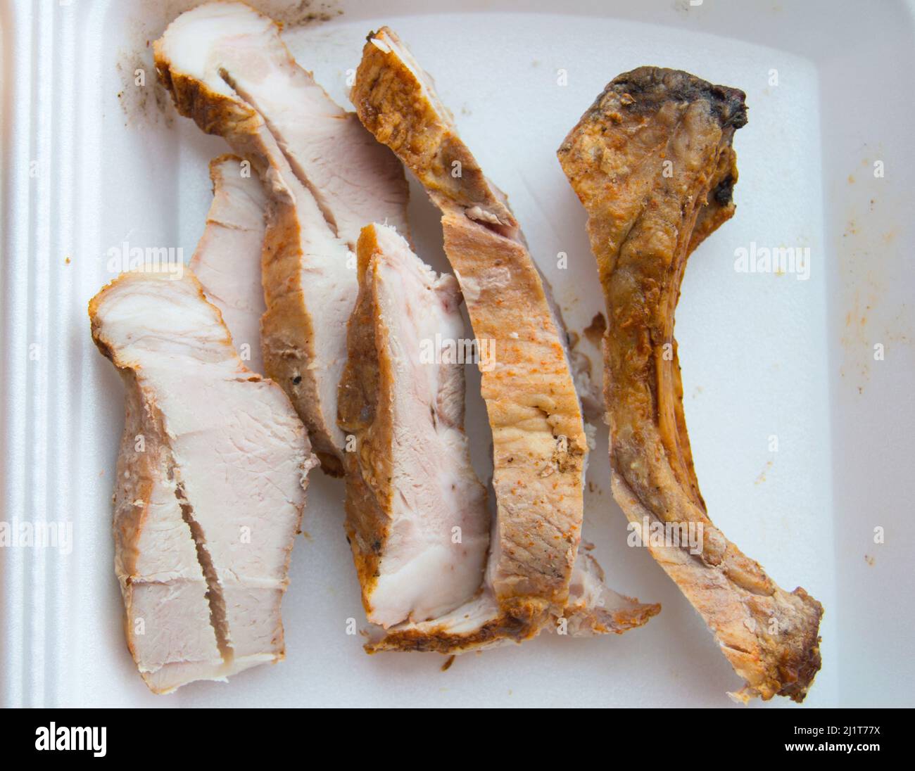 Close-up of sliced pieces of cold baked pork in a plastic container ...