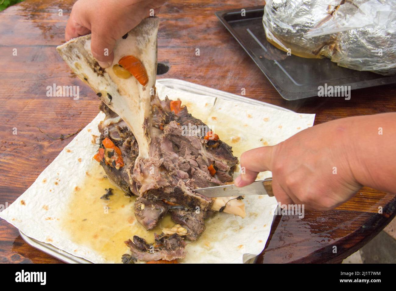 A woman's hand separates the fried meat from the bones, cutting it with ...