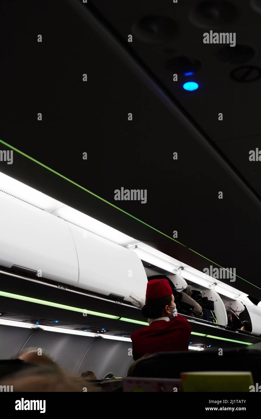 The flight attendant puts things on the luggage racks and closes the ...