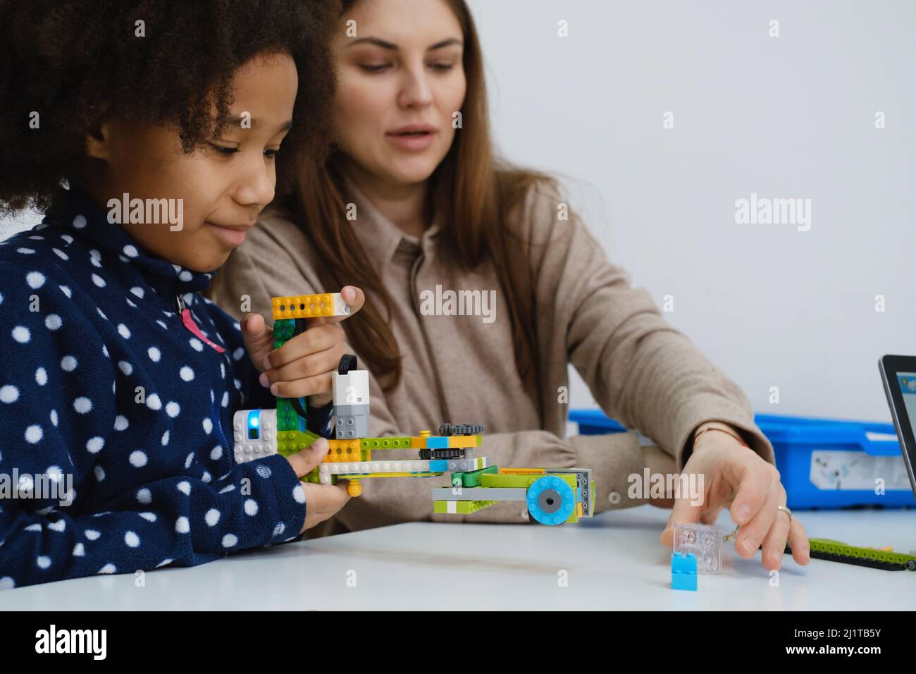 Multiethnic kids at STEM lesson constructing robot in classroom with ...