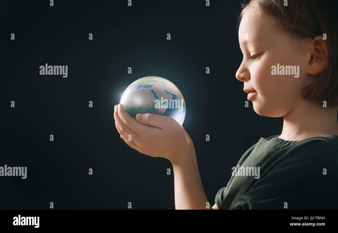 Child is holding planet in hands on darkbackground. Earth day holiday ...