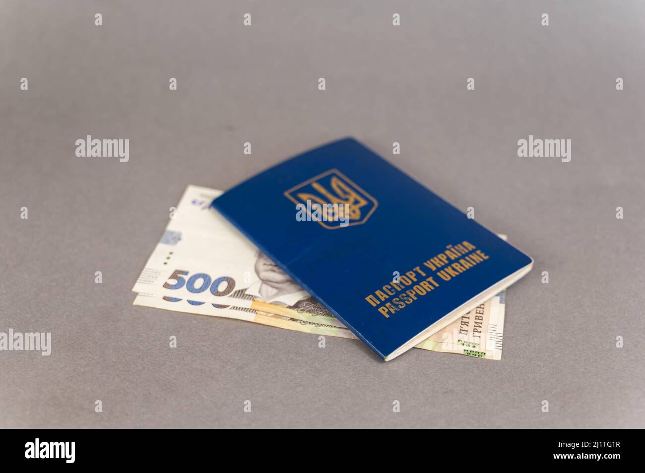 A blue covered passport and cash against a gray background. Ukrainian ...