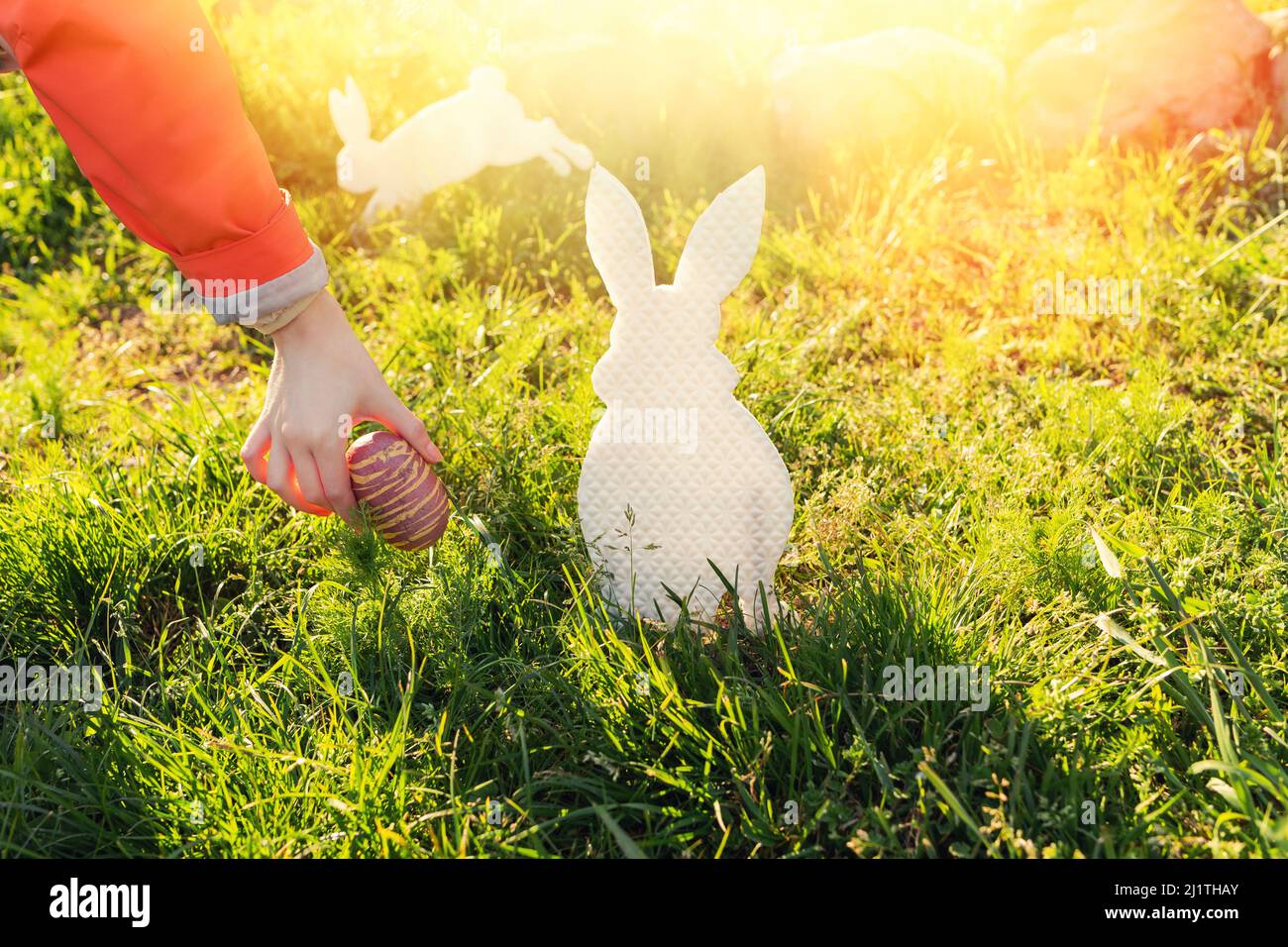 The concept of Easter holidays. The girl in orange jacket picks up a ...