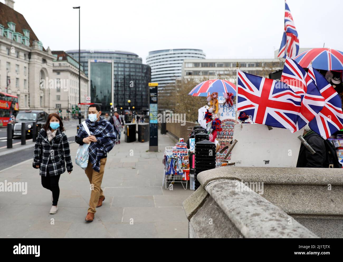 London, Britain. 27th Mar, 2022. People wearing masks walk on a street ...