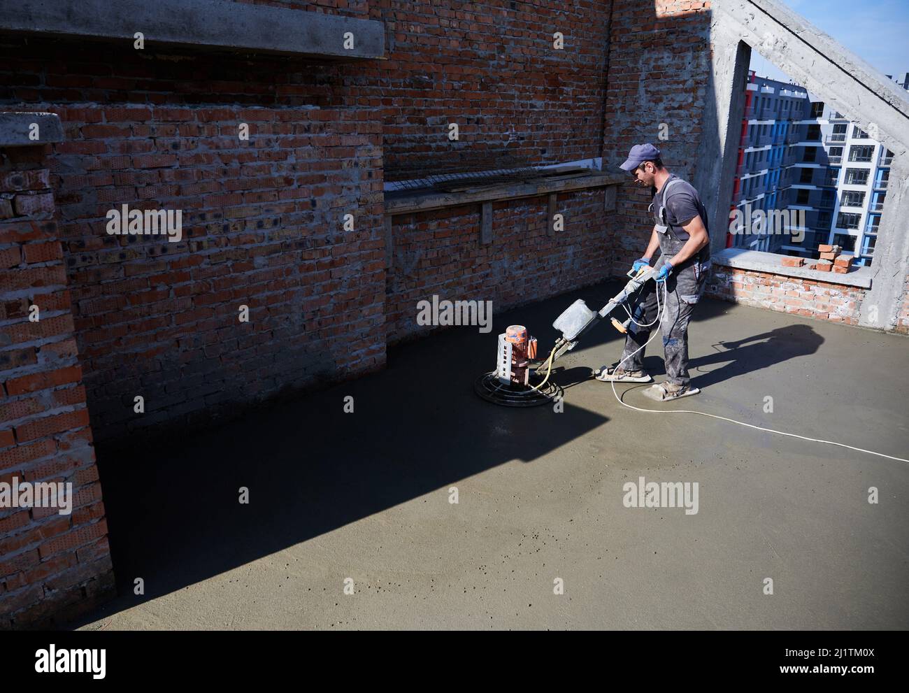 Side view of worker in uniform working with equipment and leveling the ...