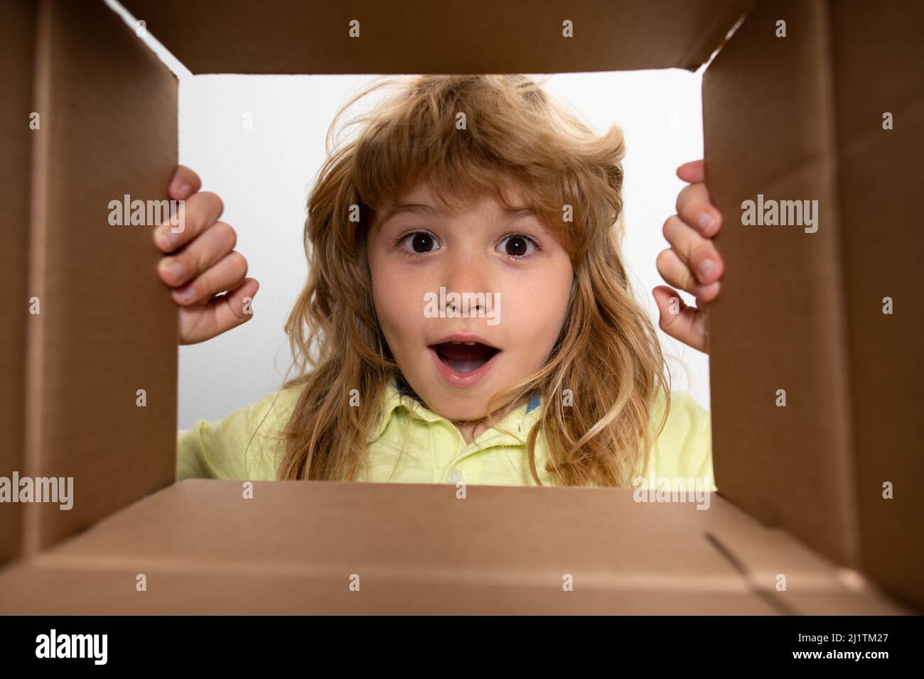 Unpacking cardboard box for kids. Happy little child boy is opening ...