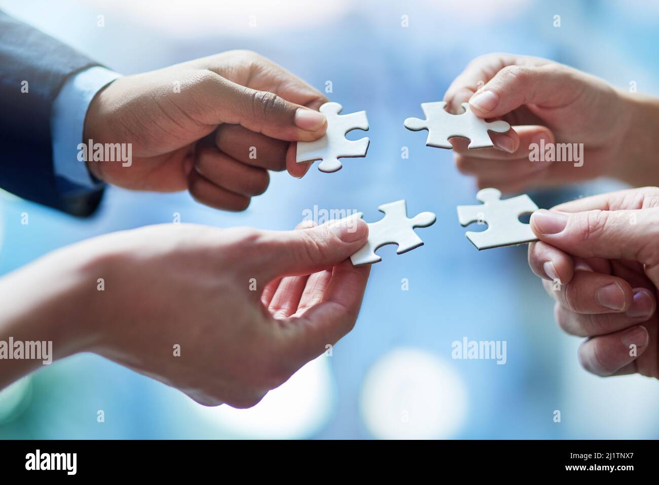 Solving the puzzle as a team. Cropped shot of people putting four ...