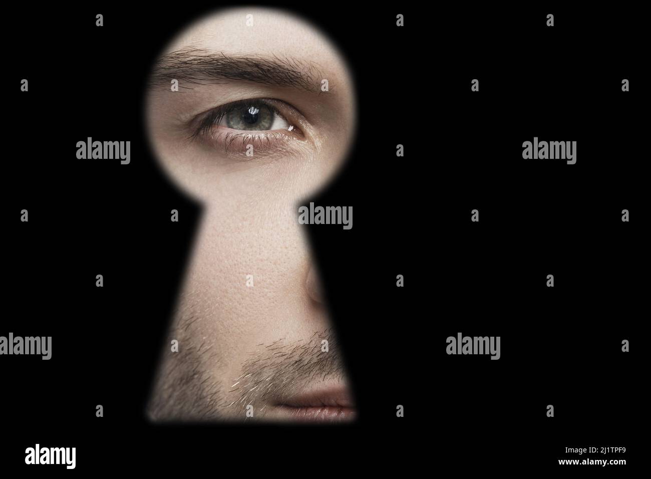 Male eye looking into the key hole Stock Photo - Alamy