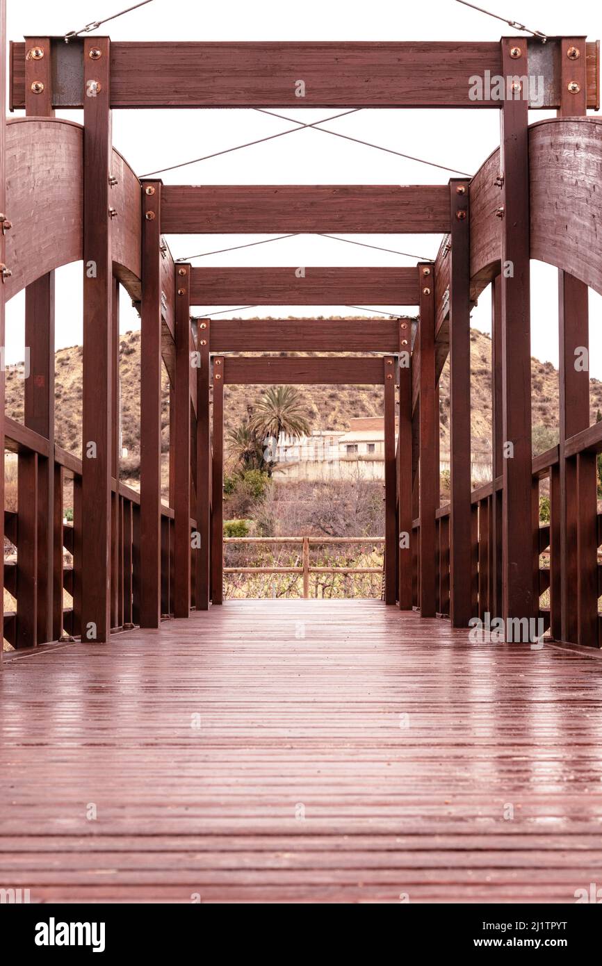 A vertical shot of the inside of a wooden bridge connecting two river ...
