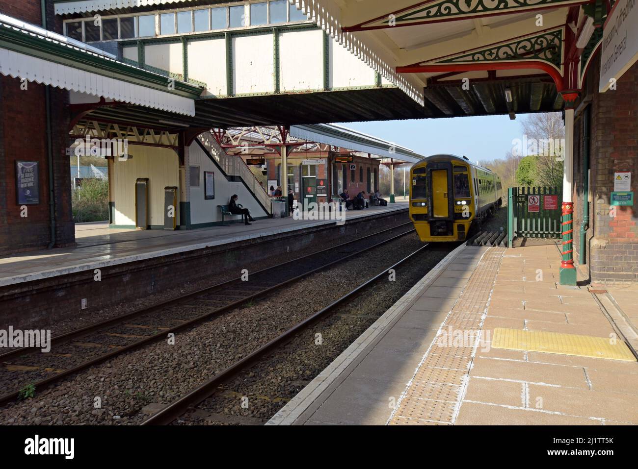 Passengers waiting on the platform as a Transport For Wales Class 158 ...