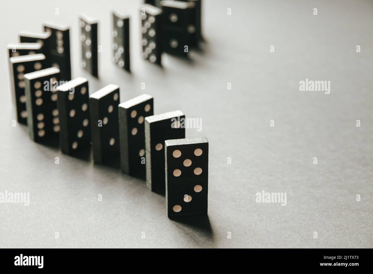 Black dominoes chain on a white table background. Domino effect concept ...
