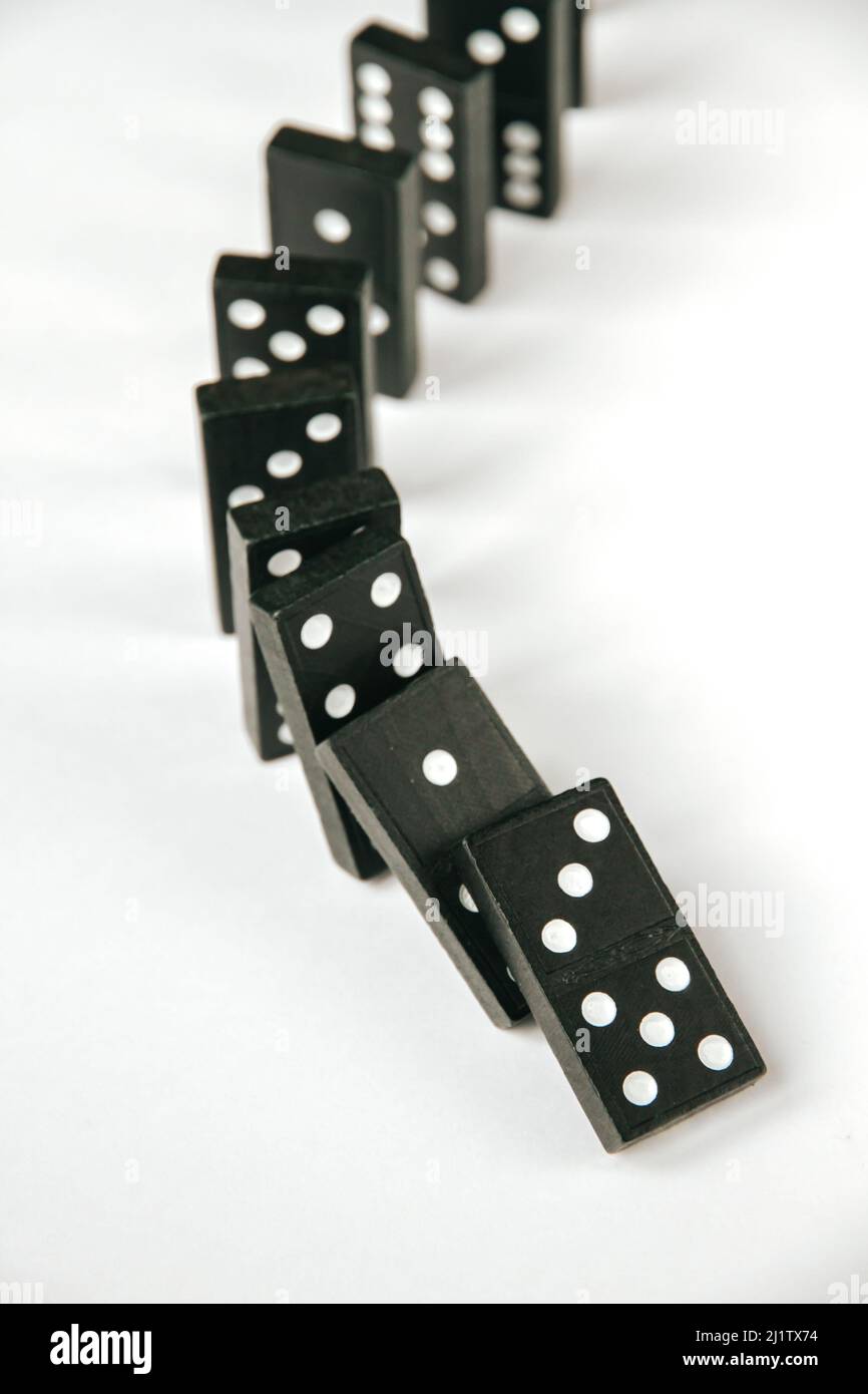 Black dominoes chain on a white table background. Domino effect concept ...
