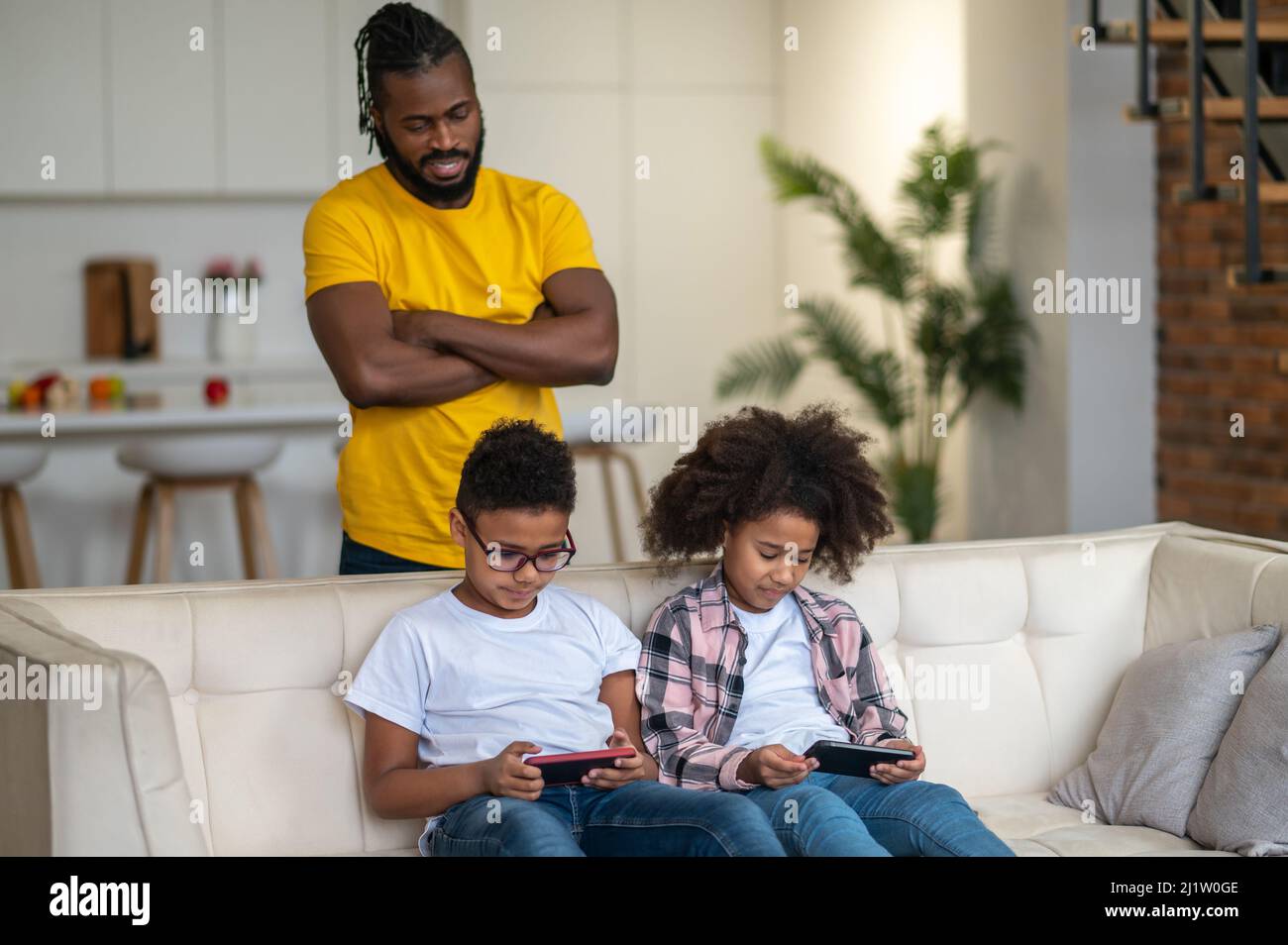 Man watching children looking at smartphones Stock Photo - Alamy