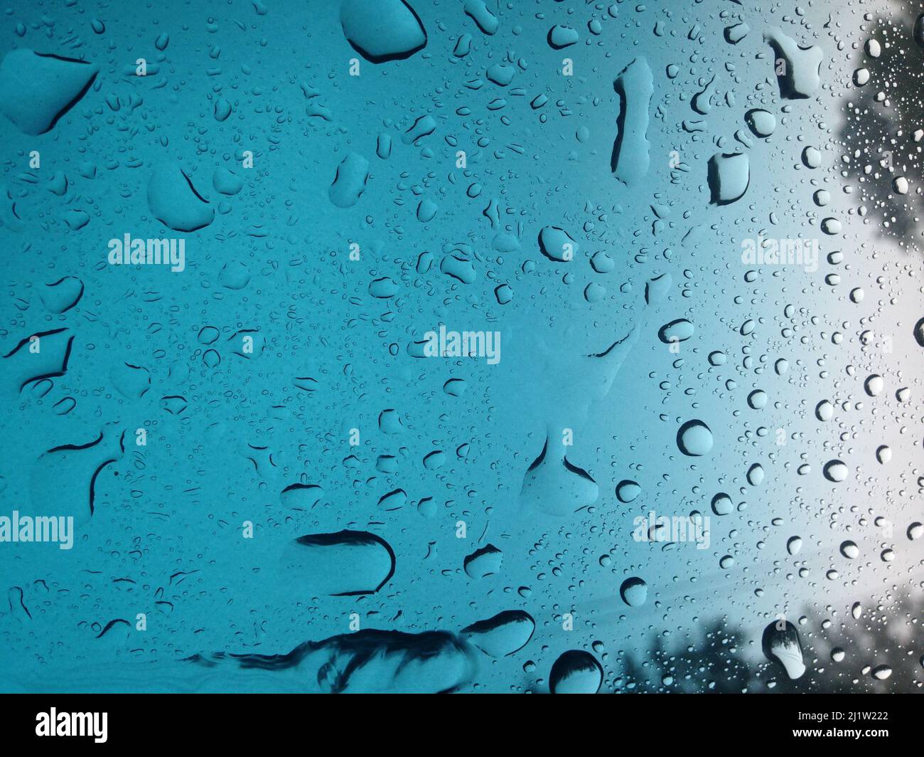 A vertical background of raindrops on a surface of a window on a blue ...