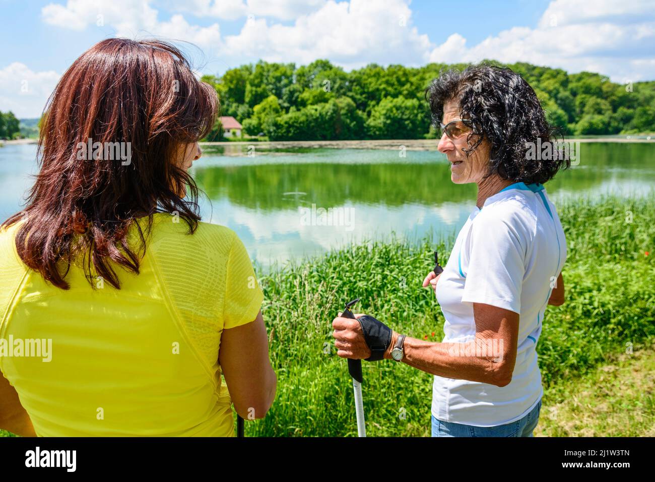 Two sporty women doing pause during a Nordic walking exercise by a ...