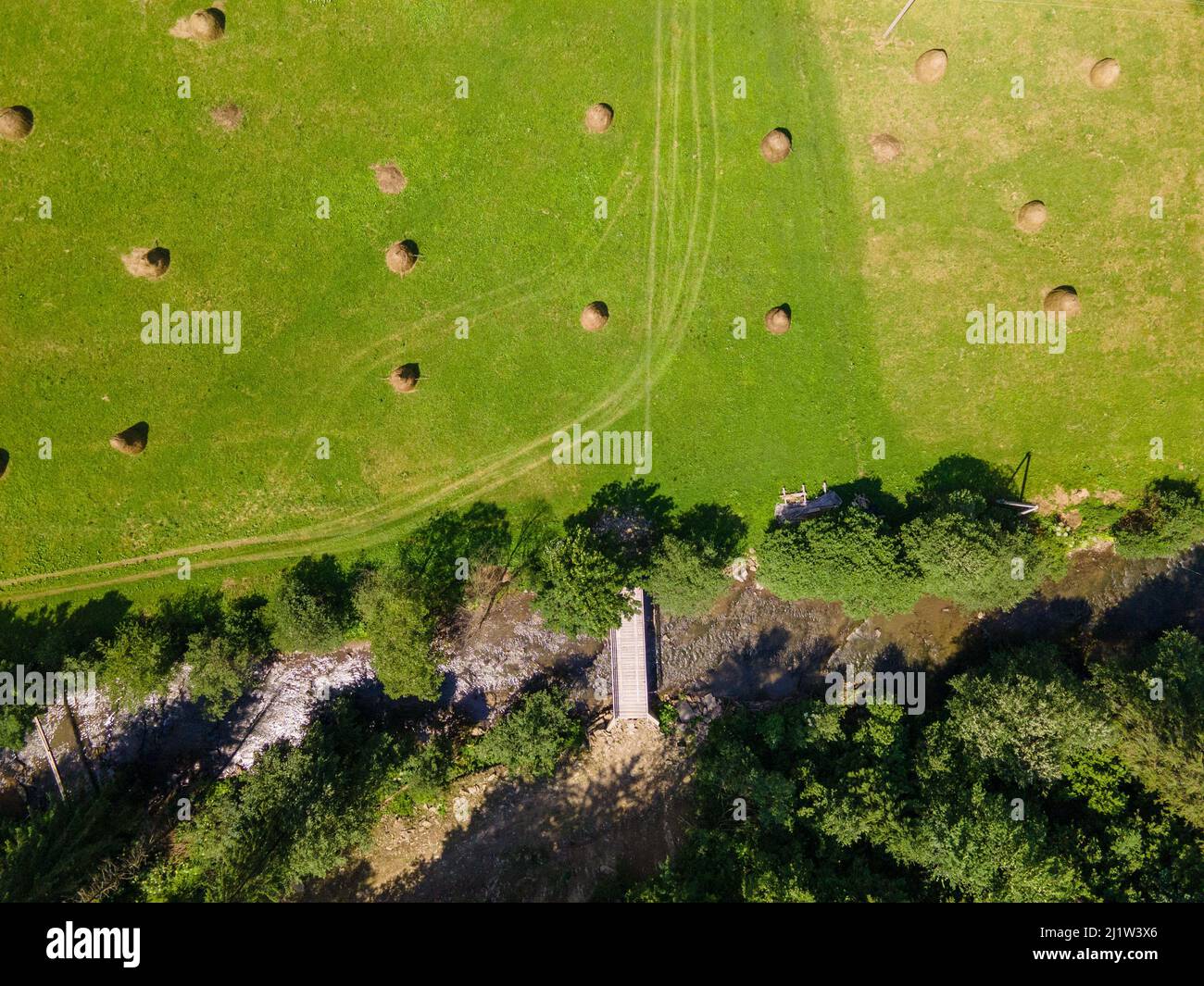 overhead view of the green field with haystack near river with bridge ...