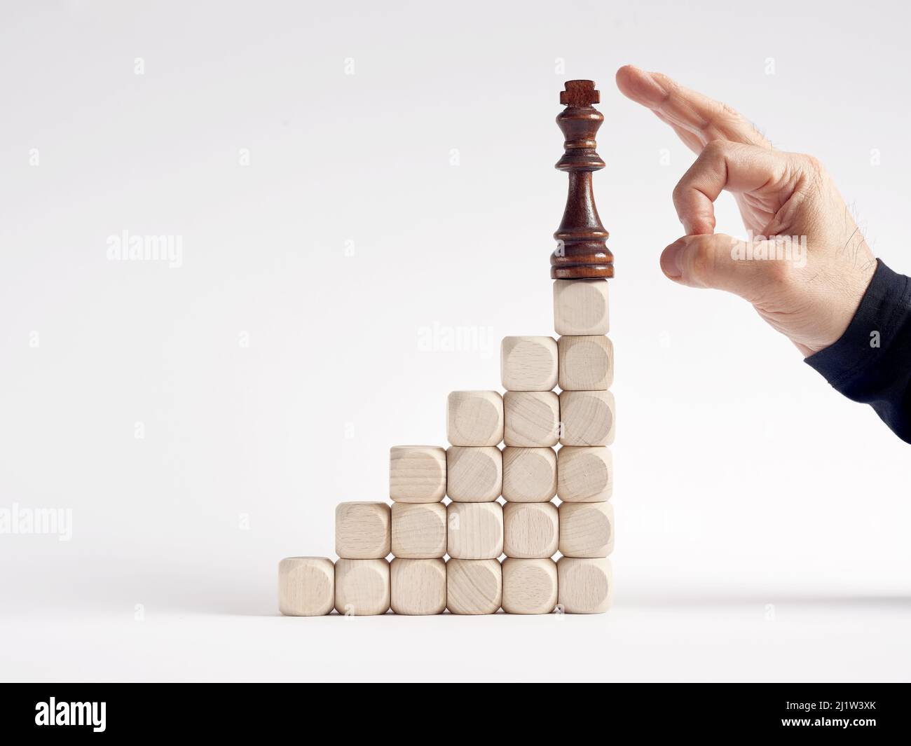 Hand is about to flick the chess king standing at the top of the ladder ...