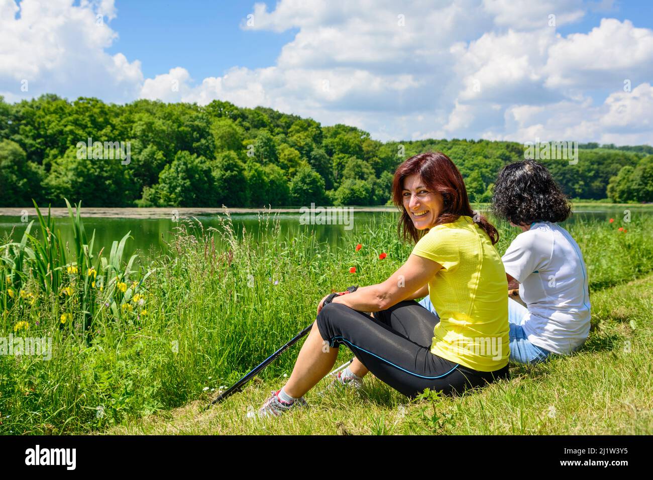 Two sporty women doing pause during a Nordic walking exercise by a ...
