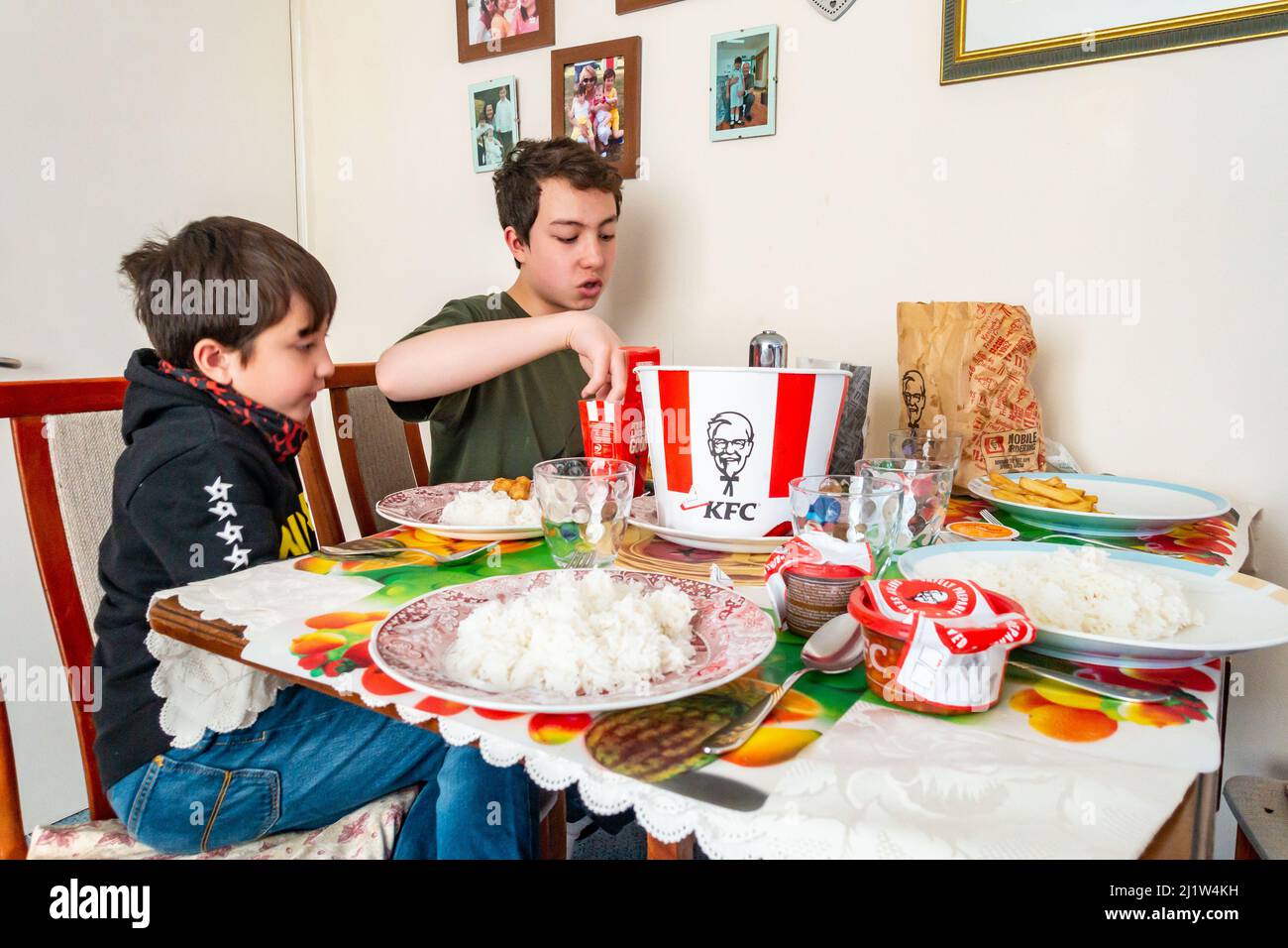 Brothers sit at a dining room table and enjoy a meal together including ...