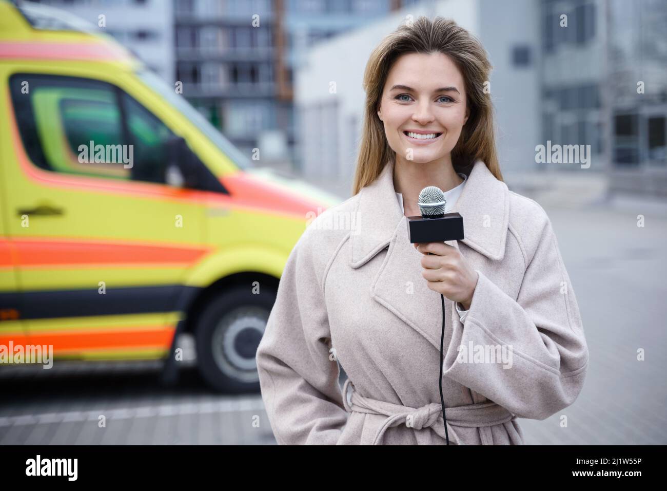 Smiling news reporter speaking into a microphone Stock Photo - Alamy