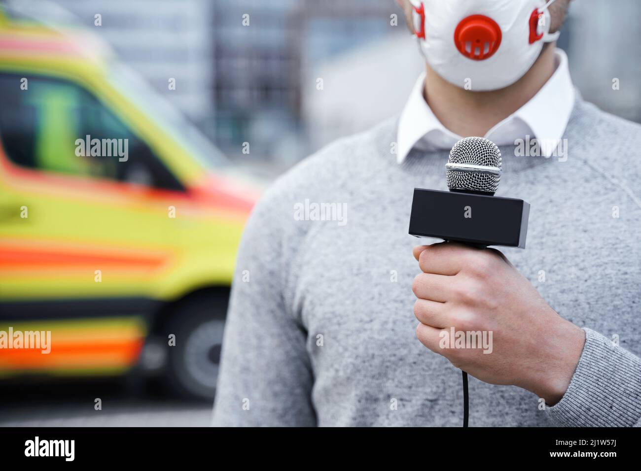 News reporter wearing a prevention mask and speaking into a microphone ...