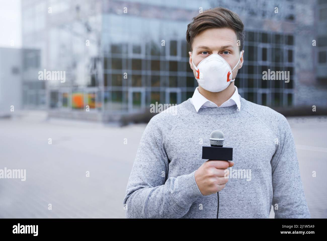 News reporter wearing a prevention mask and speaking into a microphone ...