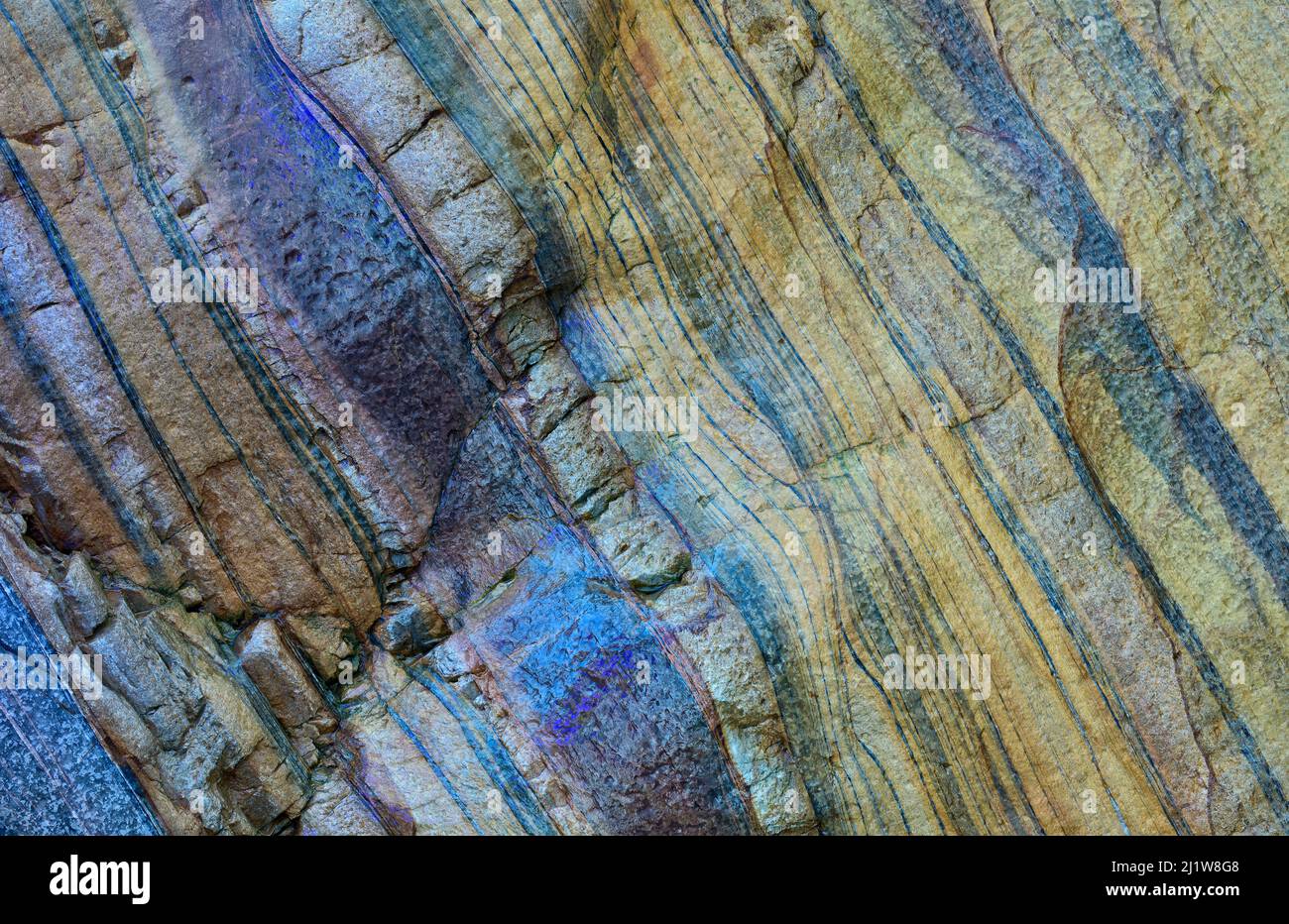 From below of massive rocky cliff with striped pattern in daytime as ...