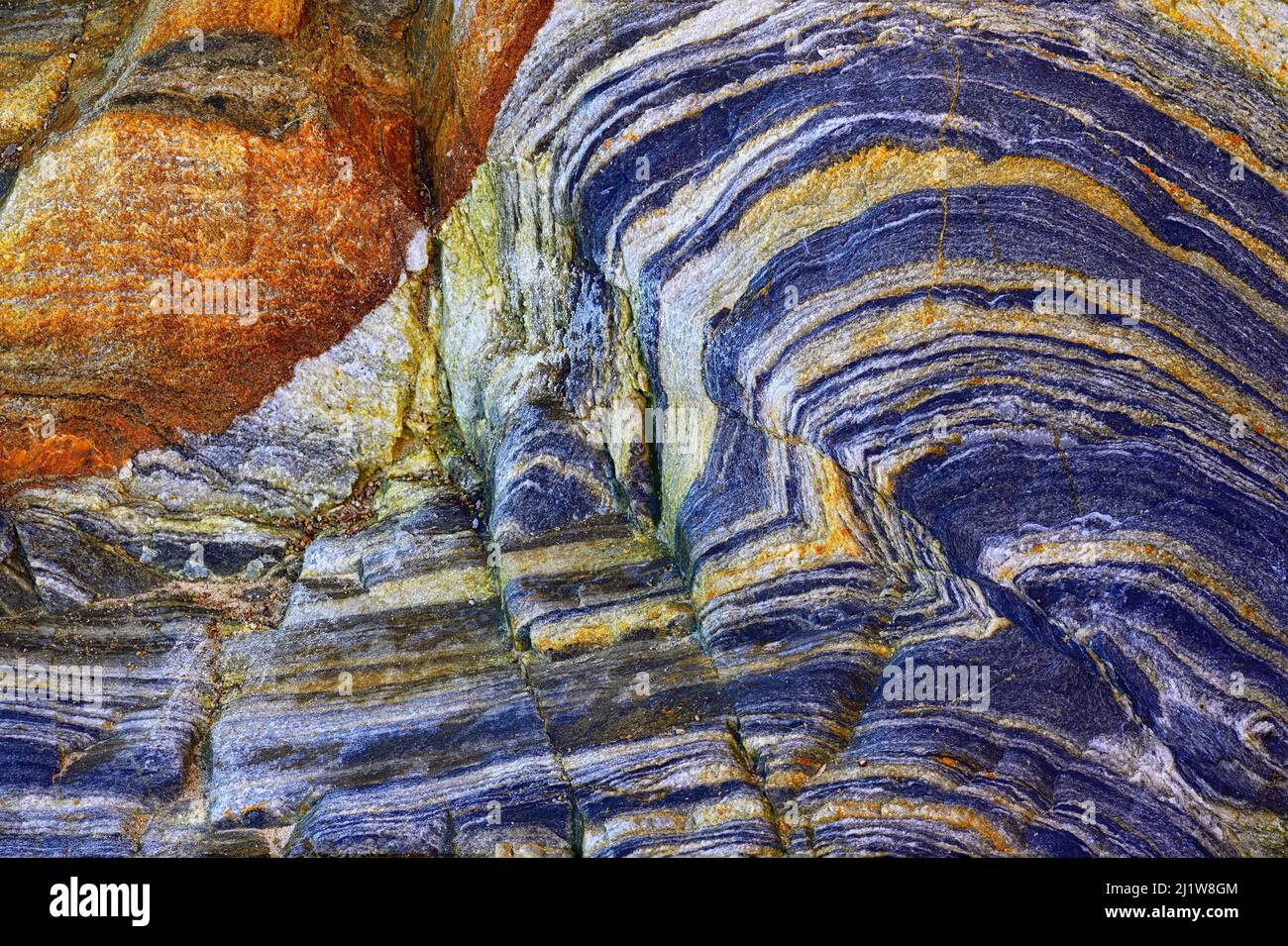 From below of massive rocky cliff with striped pattern in daytime as ...