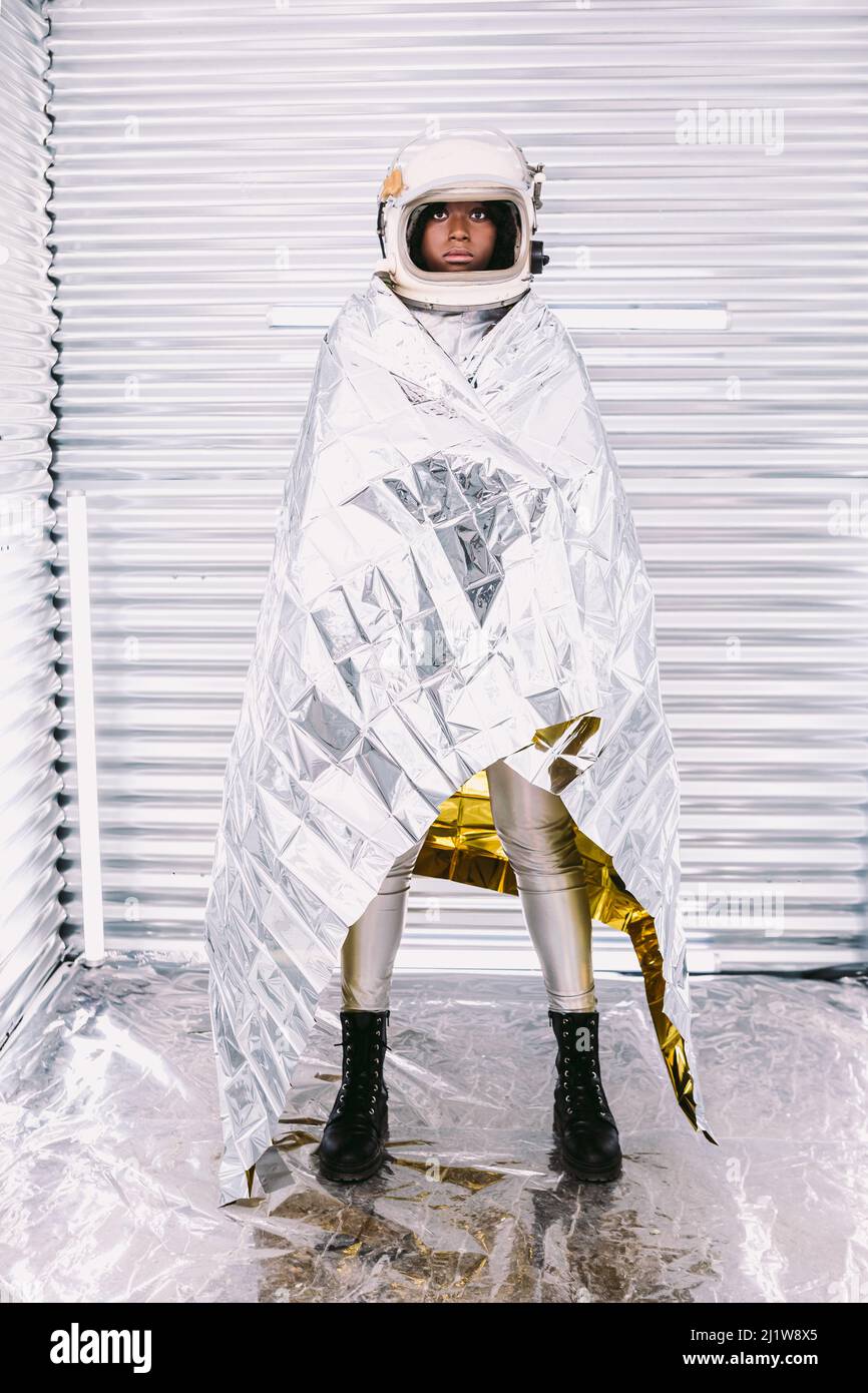 Full body of African American female cosmonaut wrapped in thermal space ...
