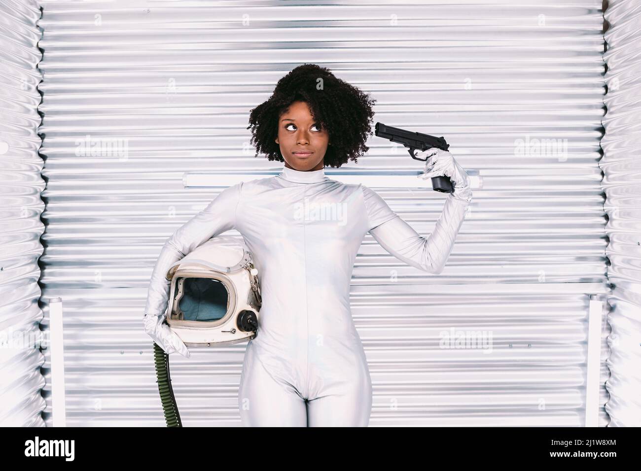 African American female cosmonaut with helmet in spacesuit pointing gun ...