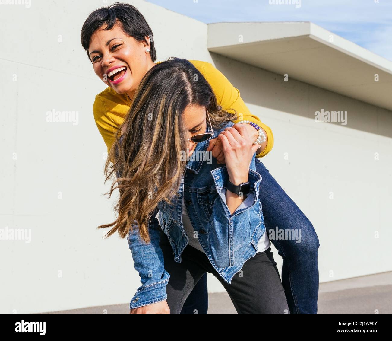 Woman giving piggyback ride to cheerful black female friend while ...