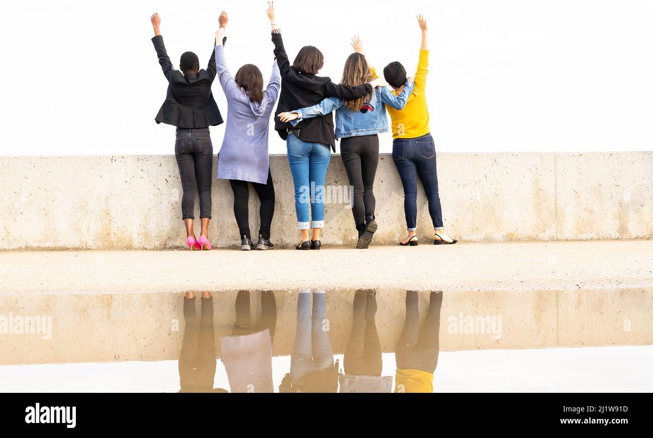 Back view full body of anonymous female friends standing near concrete ...