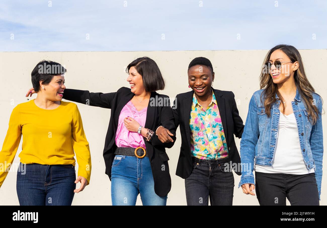 Group of cheerful multiracial female friends chatting and walking ...