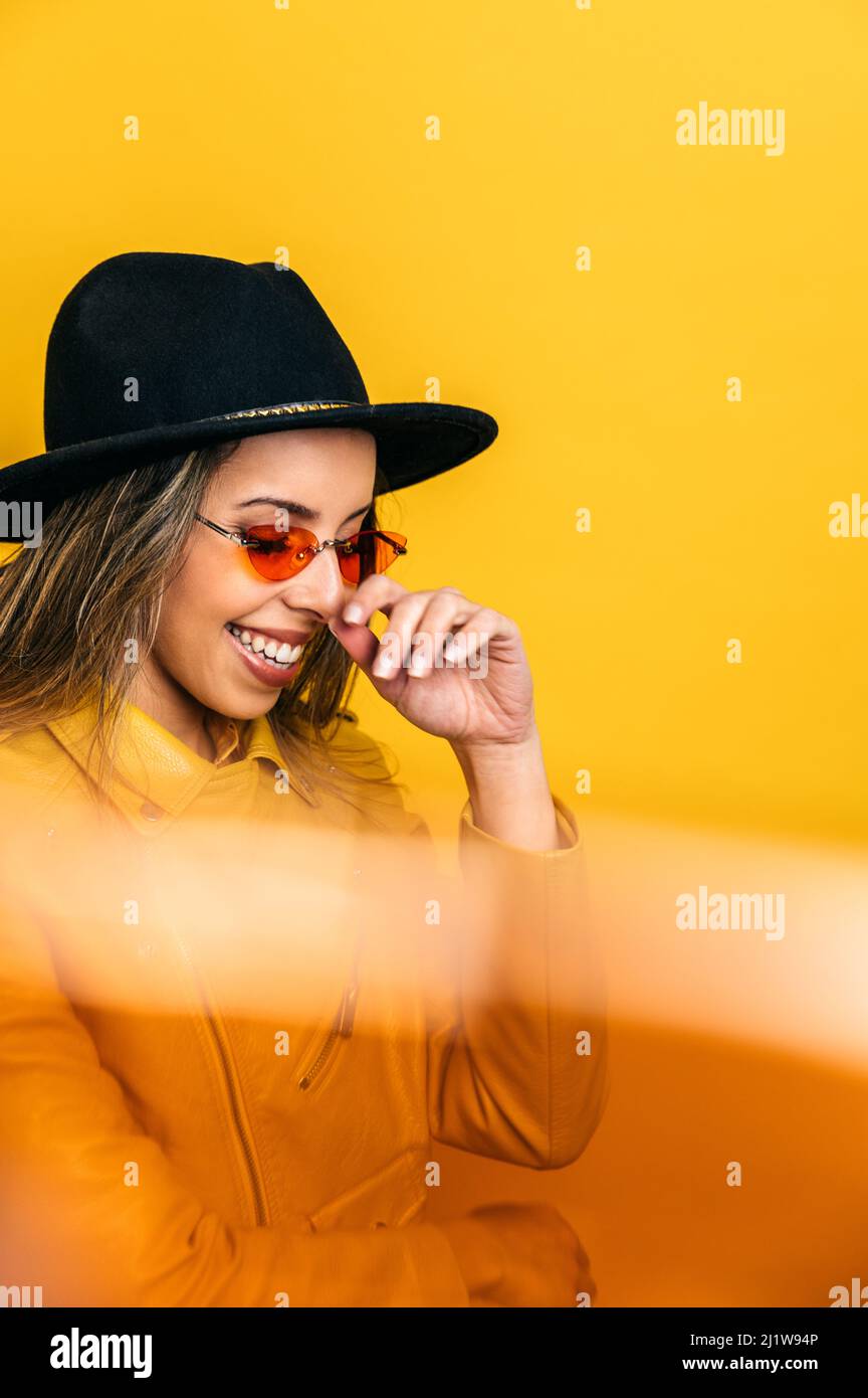 Side view of happy Hispanic female model in trendy sunglasses, hat and ...