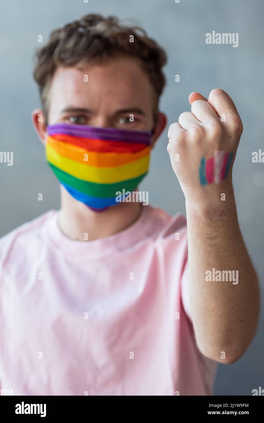 Male in protective mask with colorful LGBT rainbow pattern looking at ...