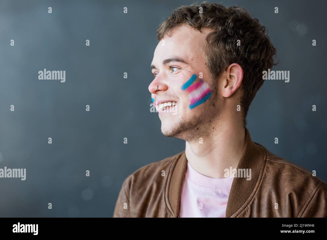 Joyful male with colorful painted blue and pink stripes representing ...