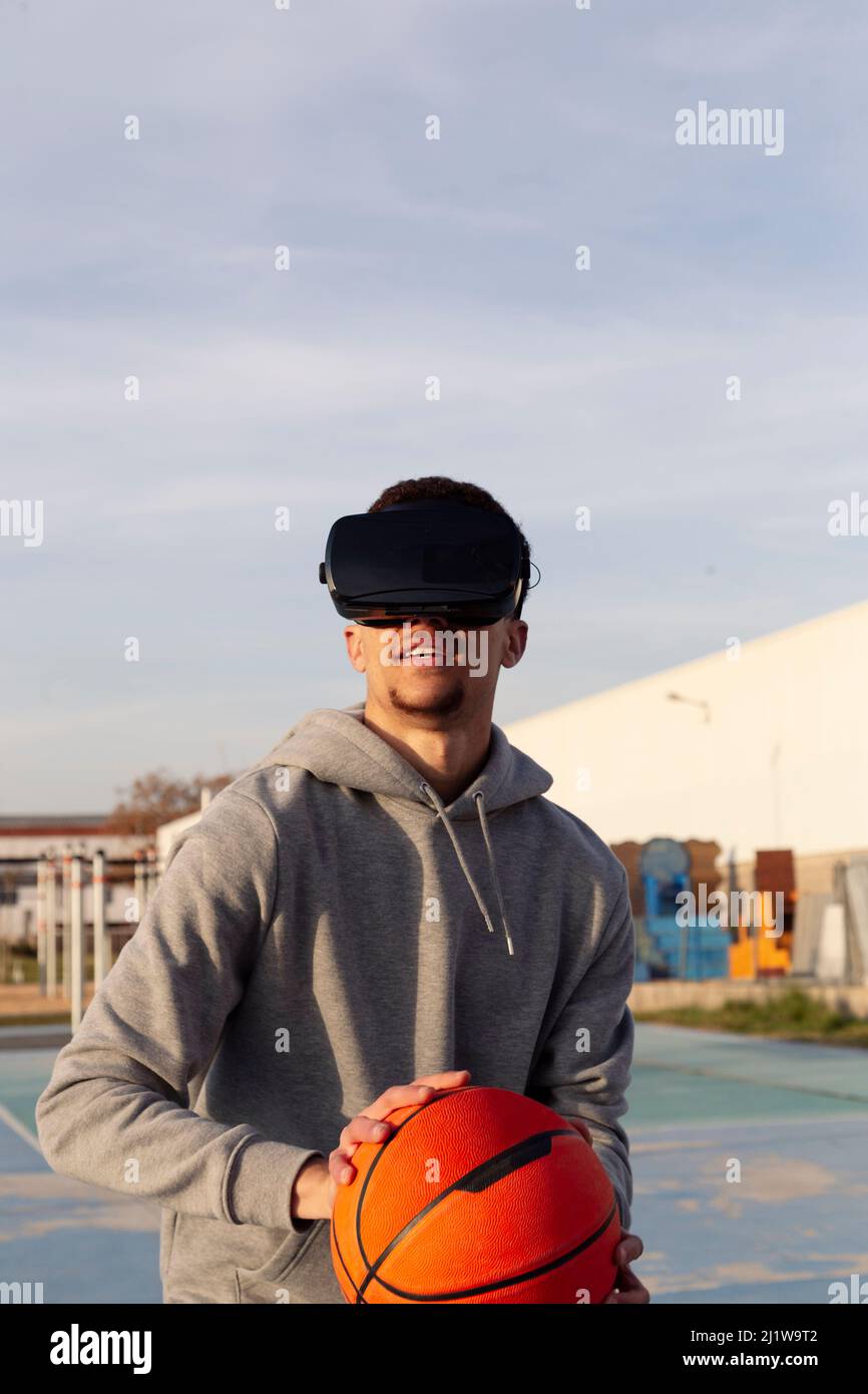 Sportsman in modern black VR goggles playing basketball while exploring ...