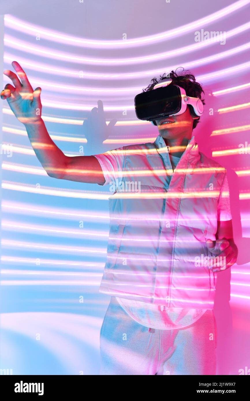 Male in modern VR goggles standing on white background in studio with ...