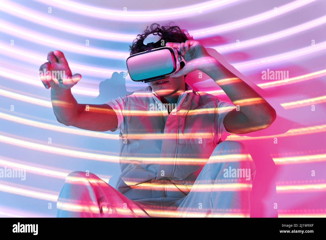 Male in modern VR goggles sitting on white background in studio with ...