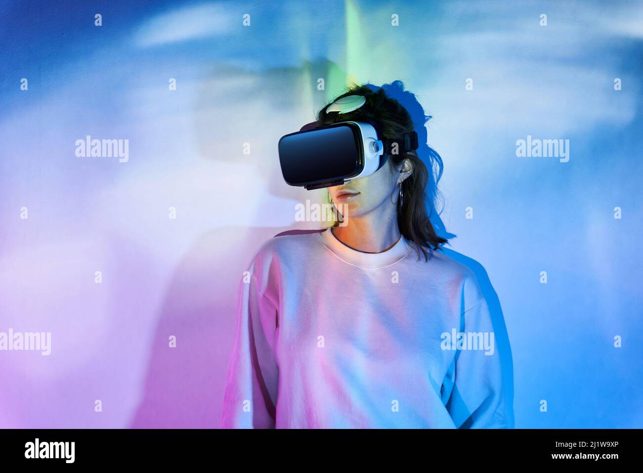 Woman in casual wear and modern black VR goggles with projected glowing ...