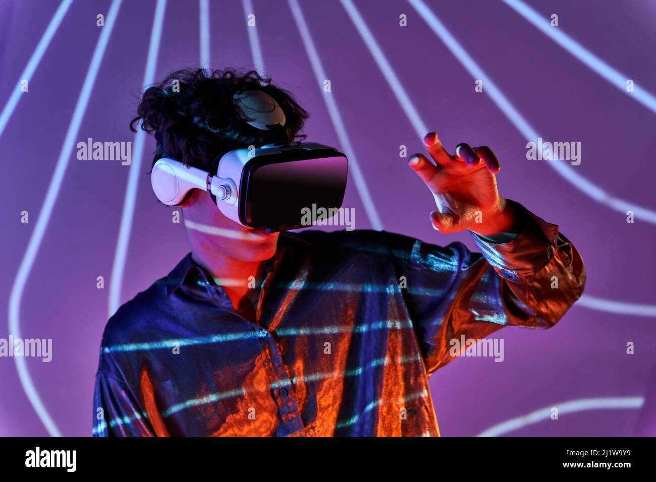 man in stylish shirt and modern VR goggles experiencing virtual reality ...
