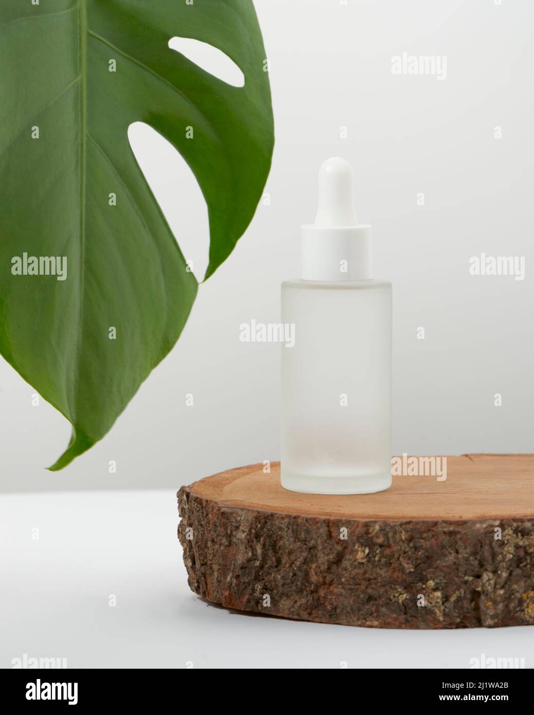 Vial filled with organic hyaluronic acid placed on round wooden board ...