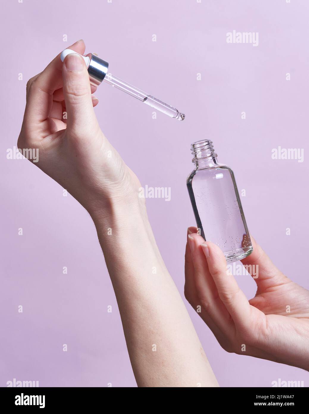 Hands of crop anonymous person dripping hyaluronic acid from pipette ...