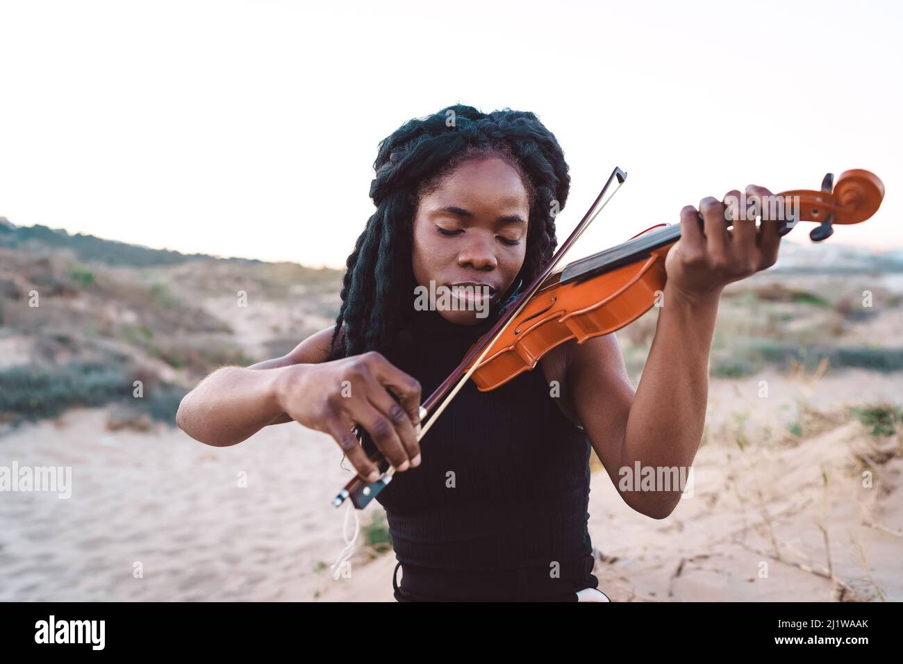Serene African American female musician playing melody on violin while ...