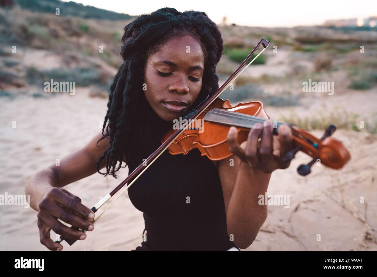 Serene African American female musician playing melody on violin while ...