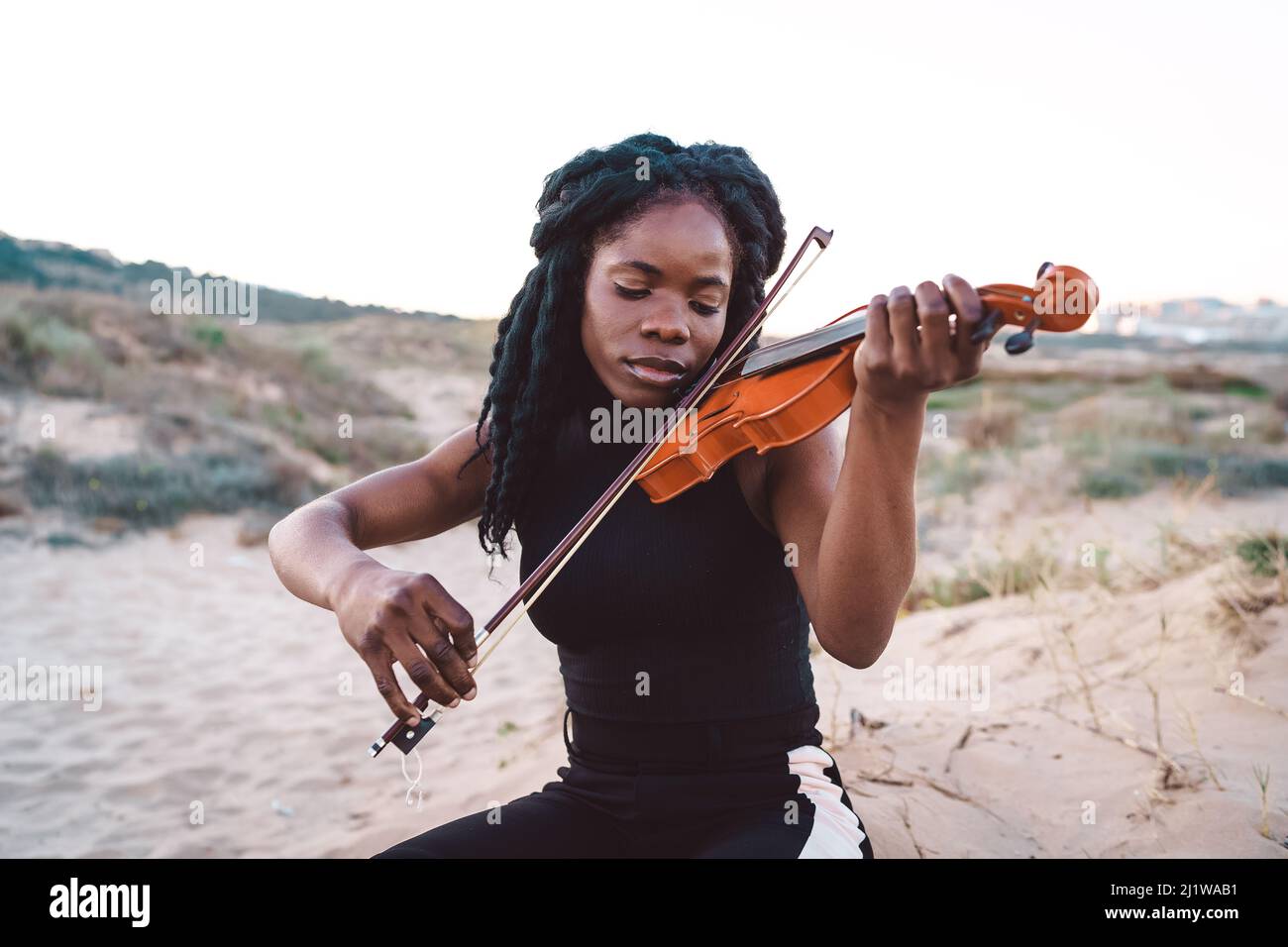 Serene African American female musician playing melody on violin while ...