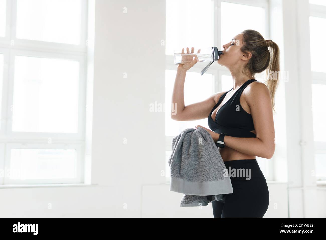 Tired sweaty woman drinks water after fitness workout in the gym Stock ...