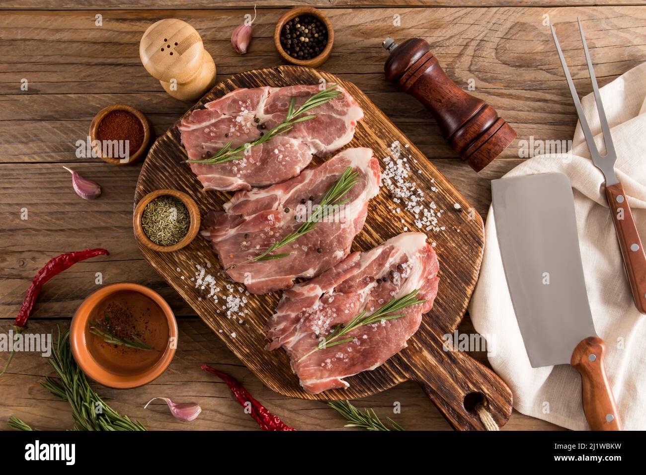 three steaks of farm pork on a wooden rustic cooking board with ...