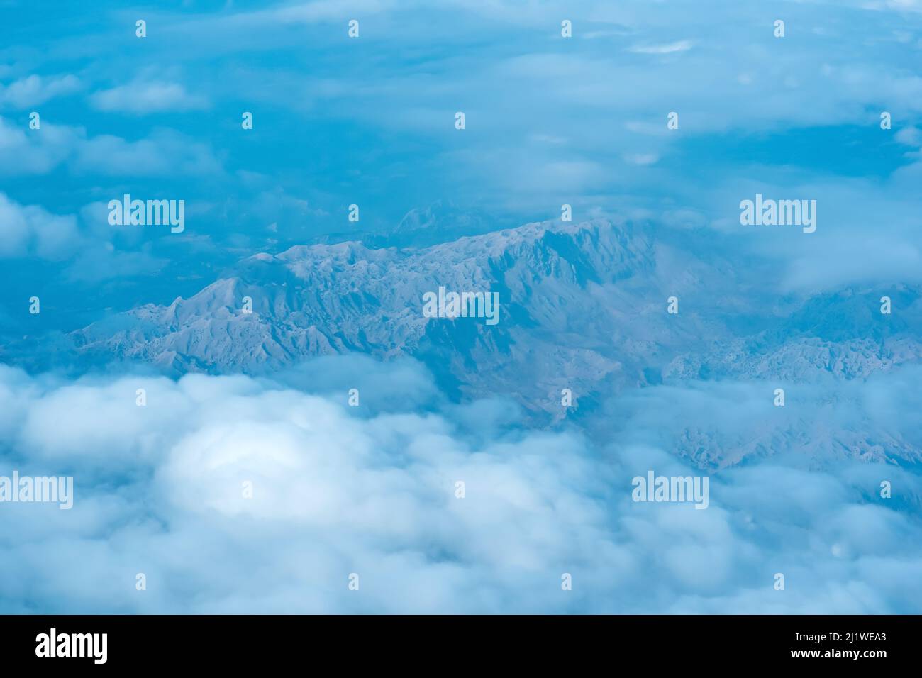 view of the earth below while flying above the clouds, mountainous ...